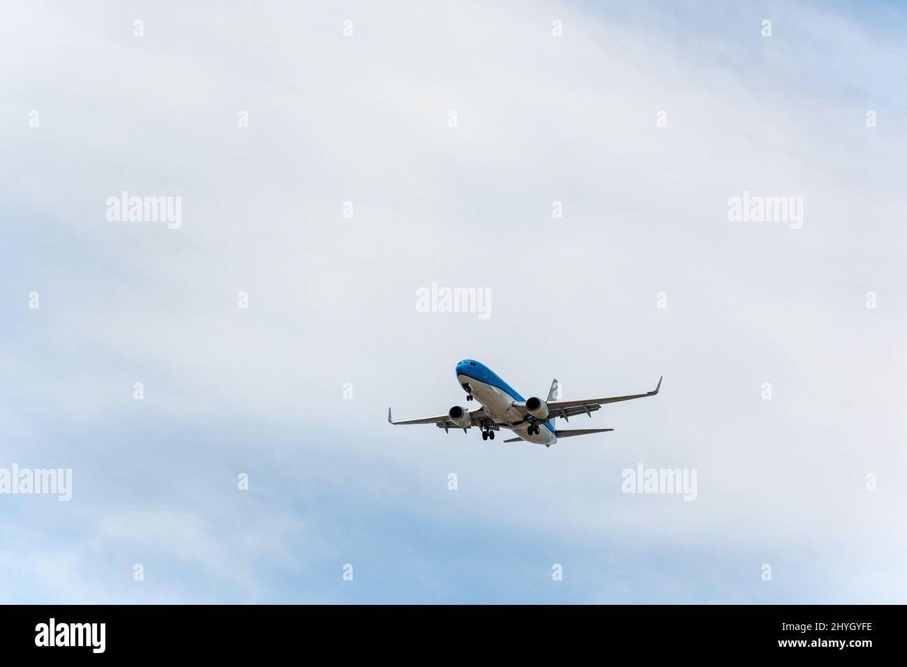 Passenger jet airplane in mid-flight against blue sky with clouds ...