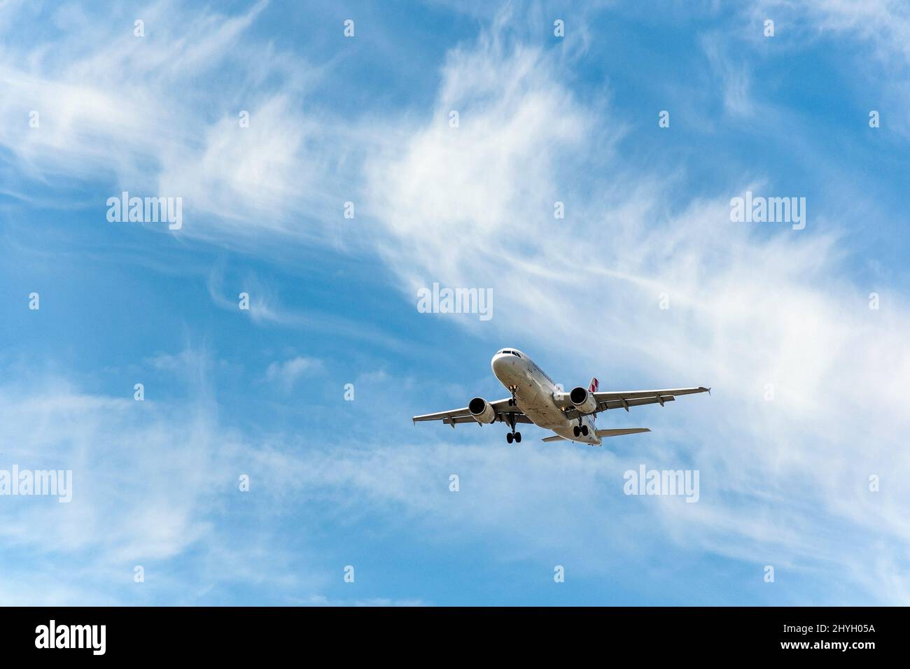 Passenger jet airplane in mid-flight against blue sky with clouds ...