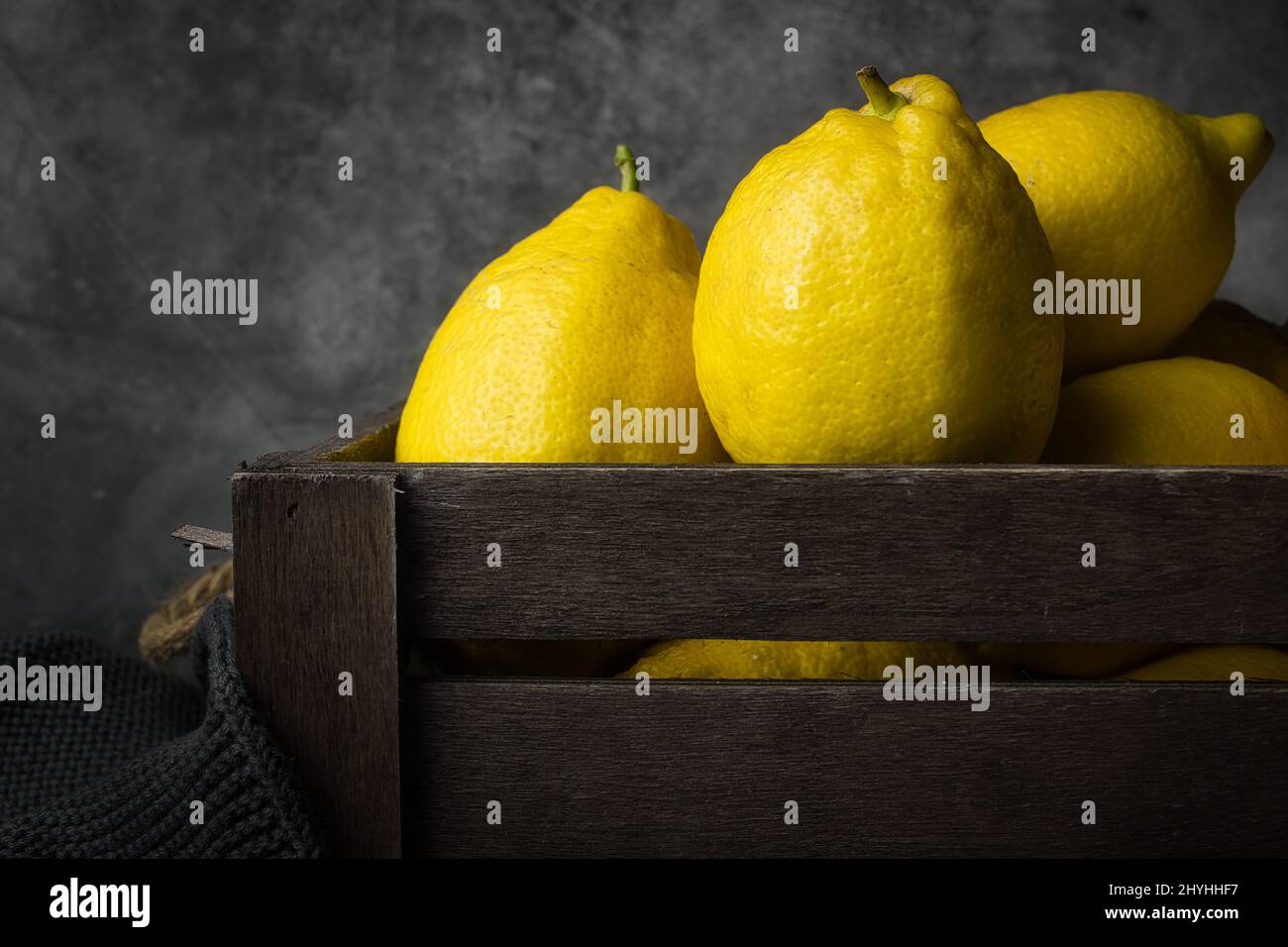 Closeup of Lemons in a vintage wooden box with a dark wall background ...