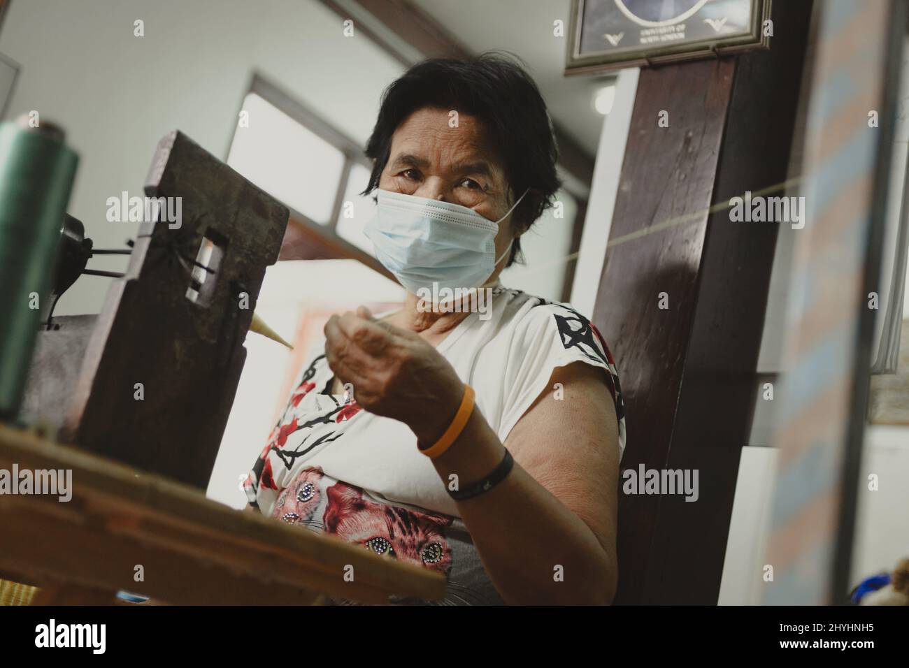Woman winds spools of silk thread at a silk weaving workshop in Bangkok ...