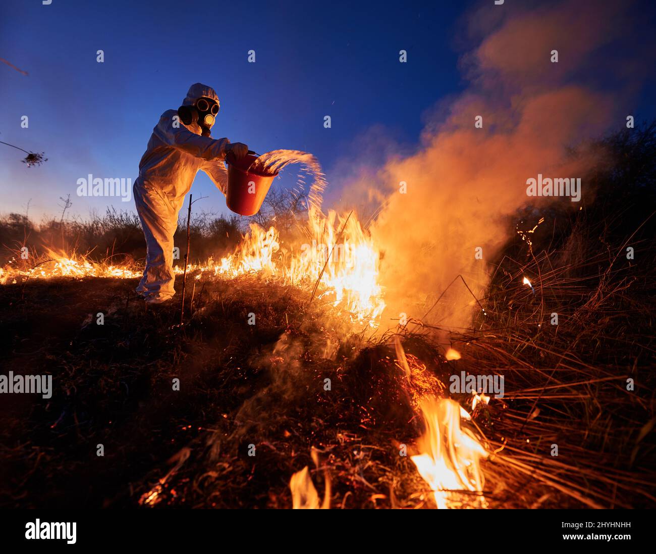 Research scientist fighting fire in field with blue night sky on ...
