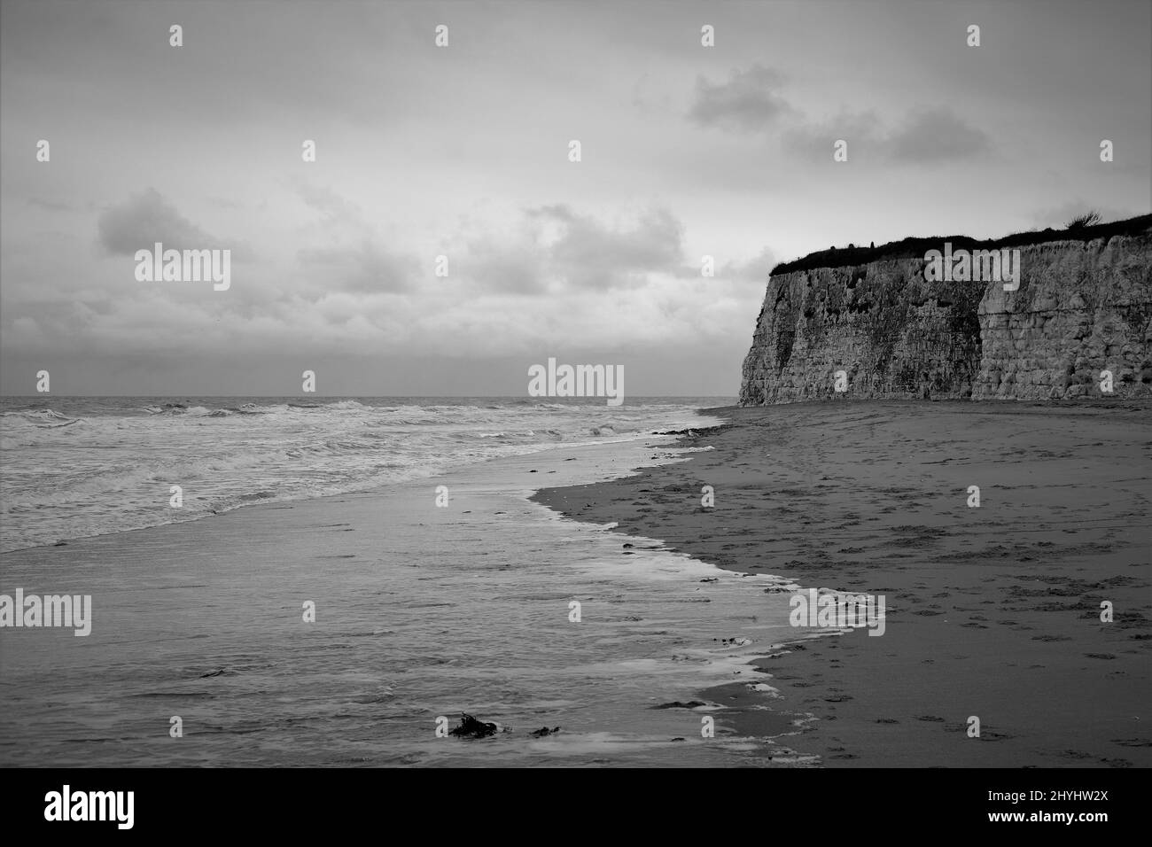 Grayscale beautiful view of a rocky cliffs in the beach by the water ...