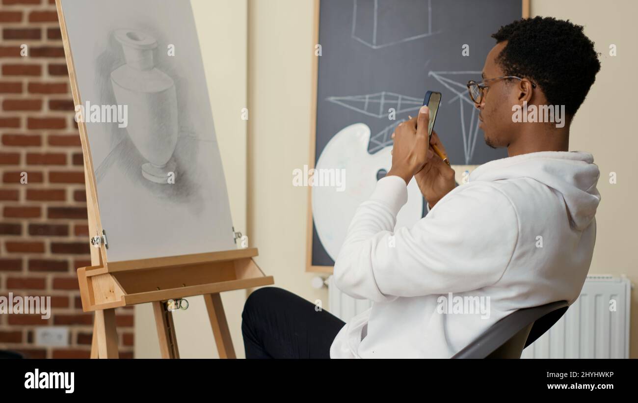 African american student using smartphone to take picture of drawing in ...