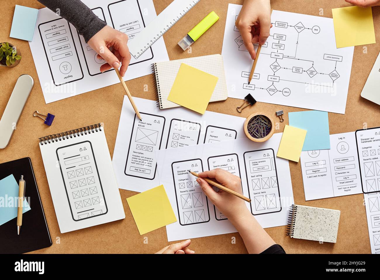 Three web UX designers working together at a busy desk with numerous ...