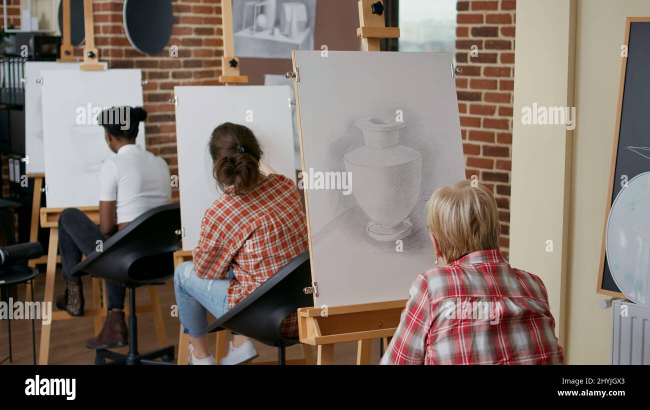 Elder student using pencil to draw on canvas in art class, attending ...