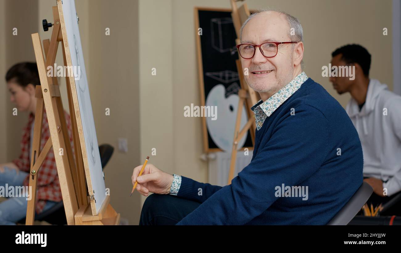 Portrait of senior man attending drawing workshop in studio to develop ...