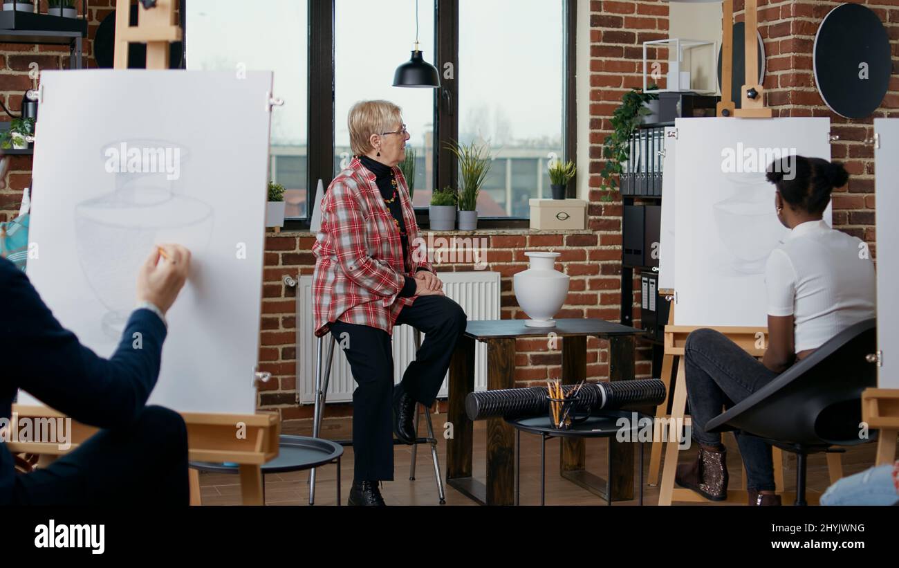 Senior woman explaining artistic vision to people in art class ...