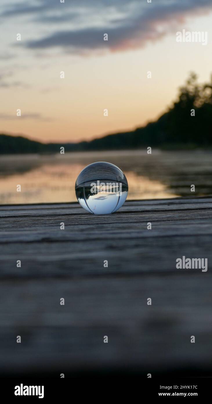 Vertical closeup of a glass ball on the wooden surface reflecting the ...