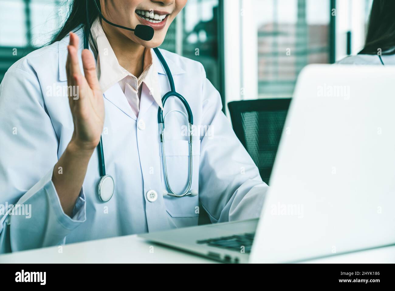 Doctor wearing headset talking actively on video call in hospital or clinic . Concept of ...