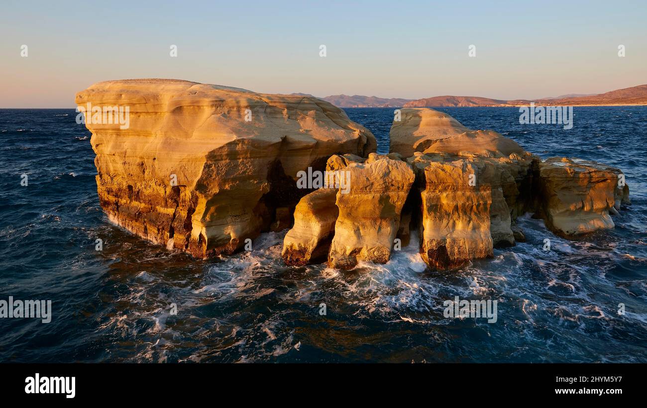 Evening light, rocky island surrounded by surf, ochre tuff, sky light ...