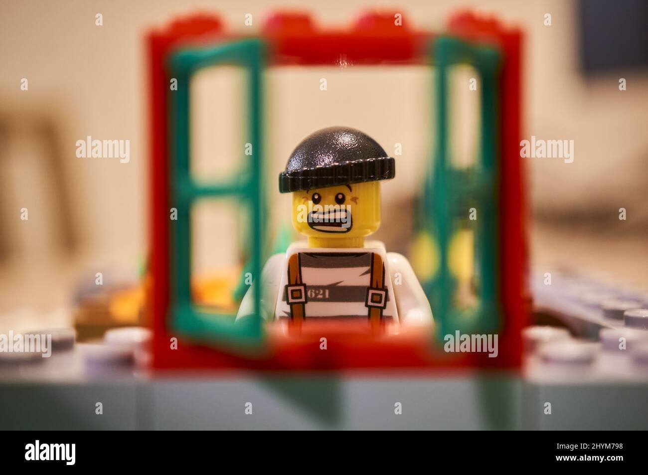 Selective focus of a Lego scared prisoner toy looking through a window ...