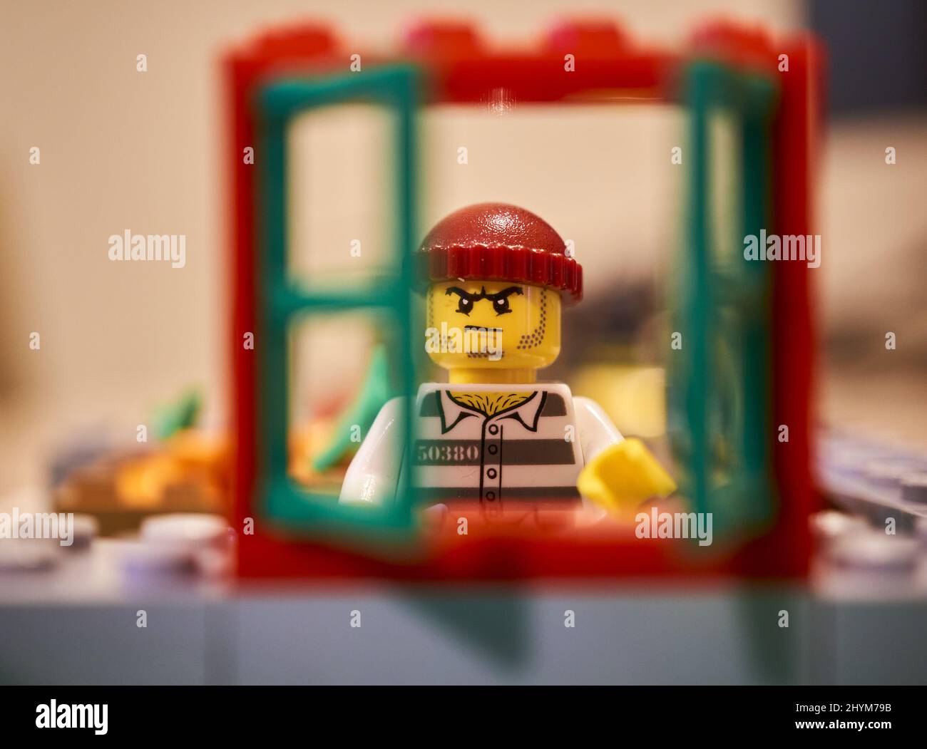 Selective focus of a Lego angry prisoner toy looking through a window ...