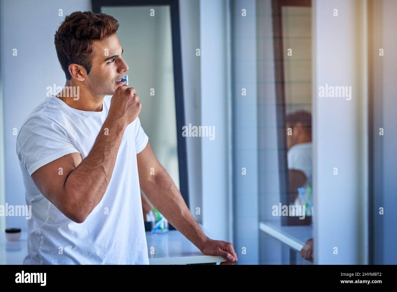 Deep in the morning routine zone. Shot of a handsome young man looking ...