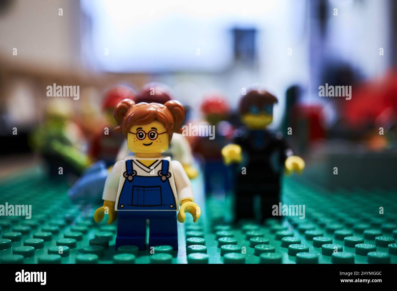 Selective focus of a small girl Lego toy with glasses on a blurry background of other Legos ...