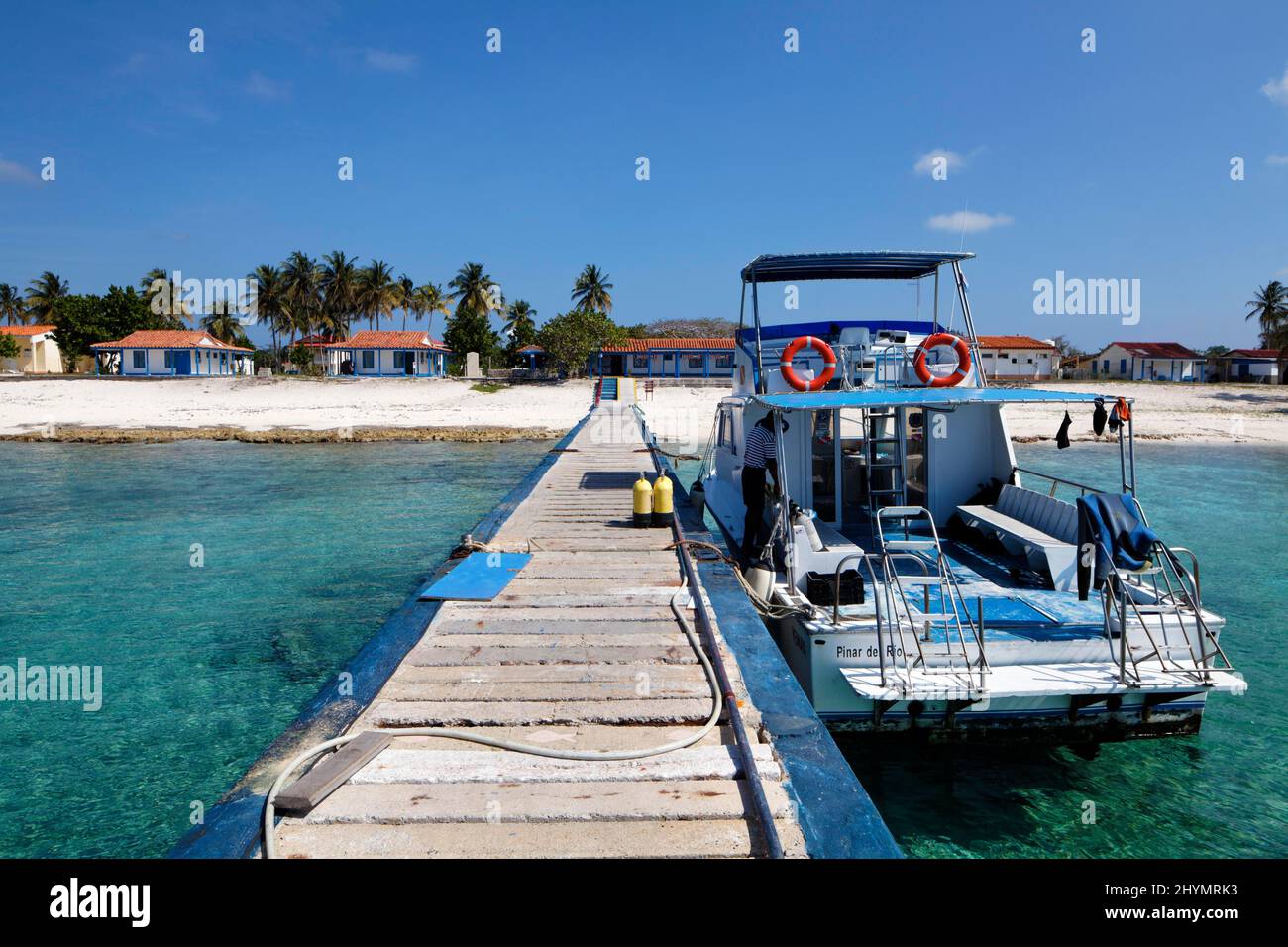 Dive shop boat at the jetty, bungalows and dive centre in the back ...