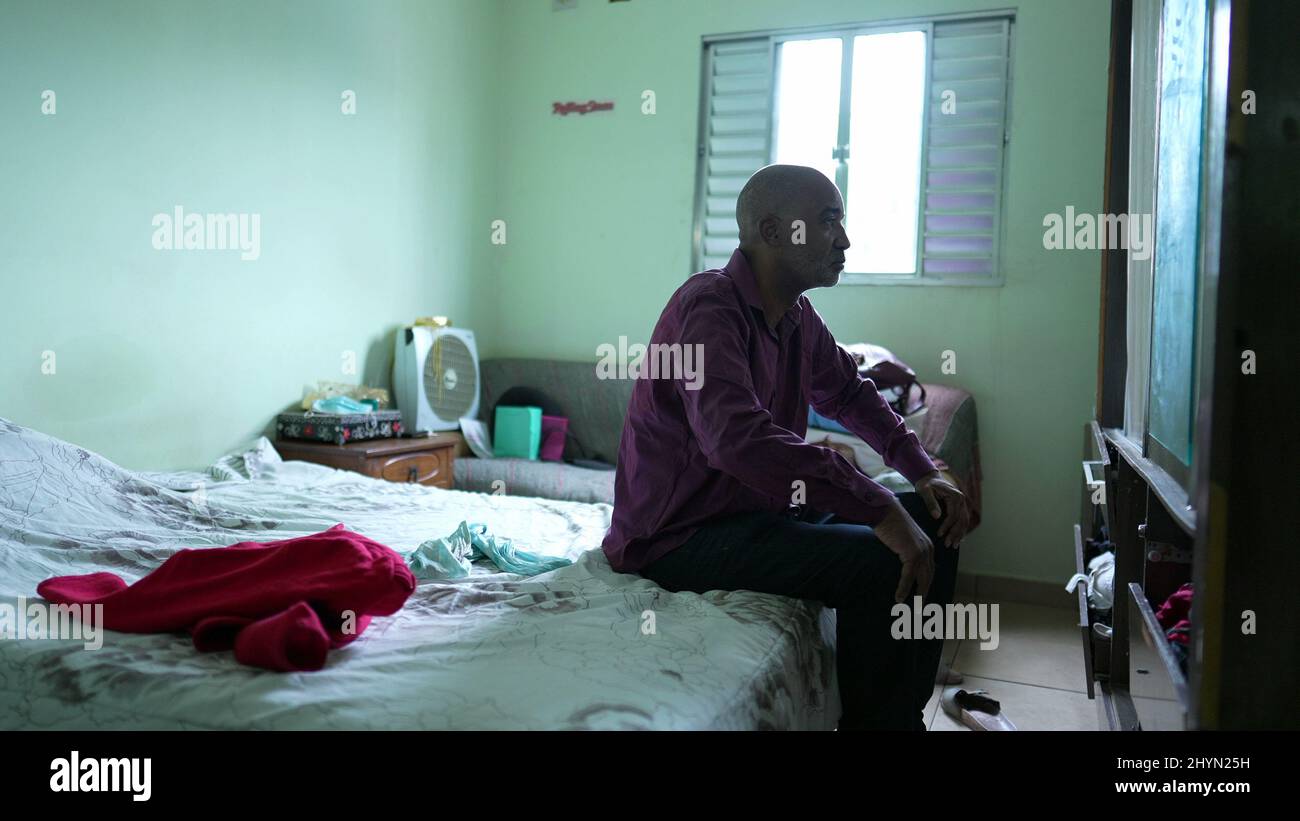 A thoughtful African man in bedroom thinking about life during middle ...