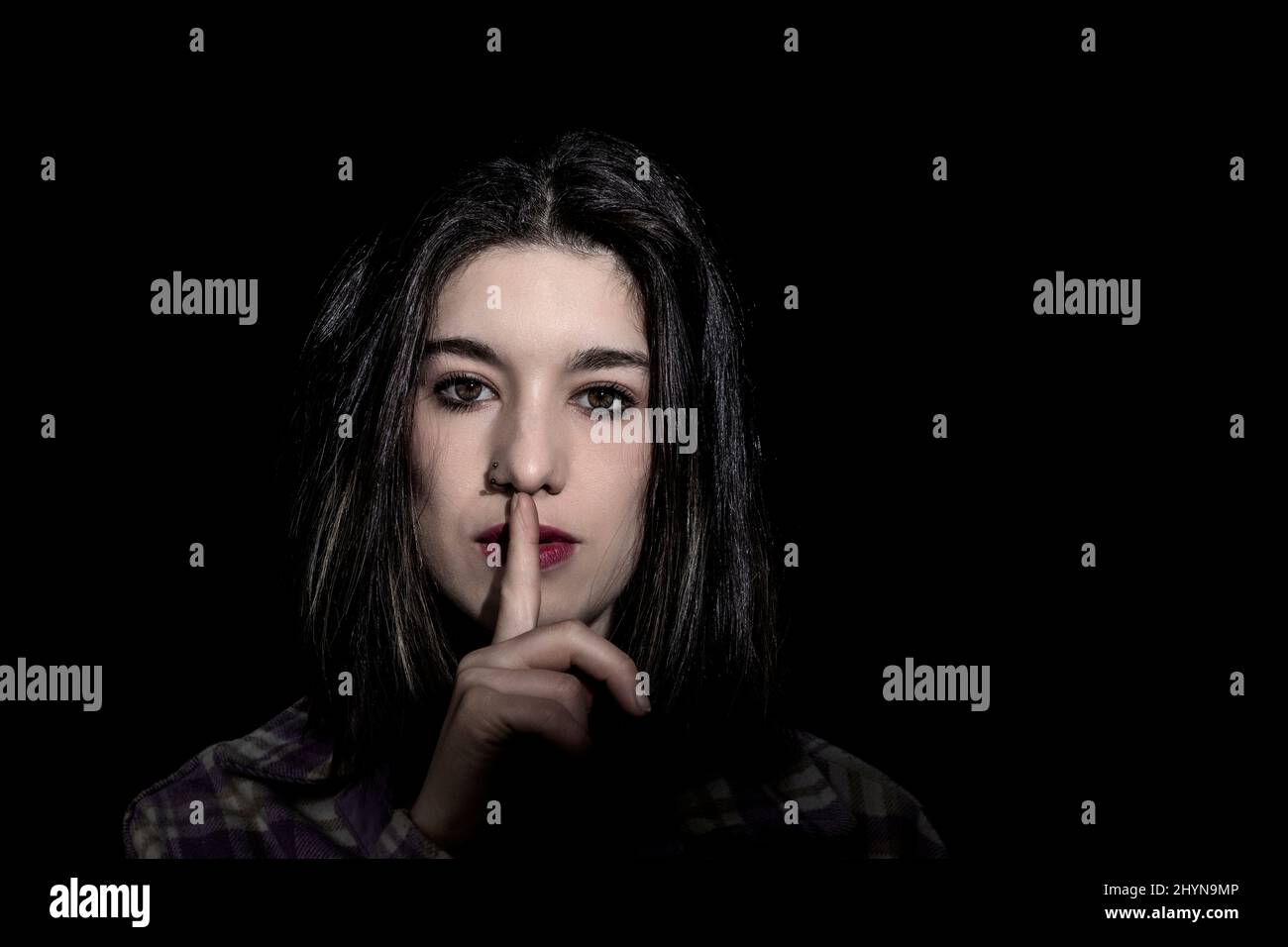 brunette woman commanding silence on black background Stock Photo - Alamy
