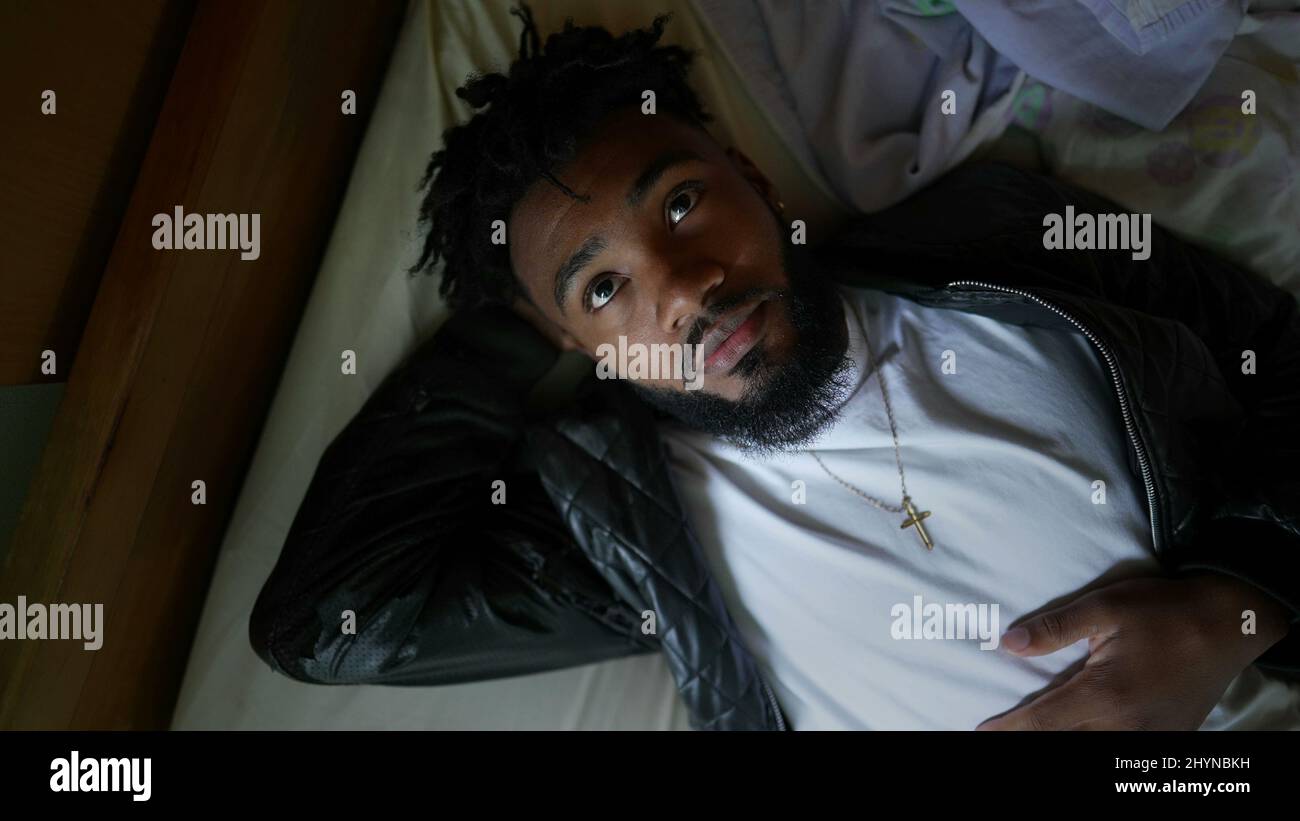 A pensive black man lying down in bed a resting young African man daydreaming Stock Photo - Alamy
