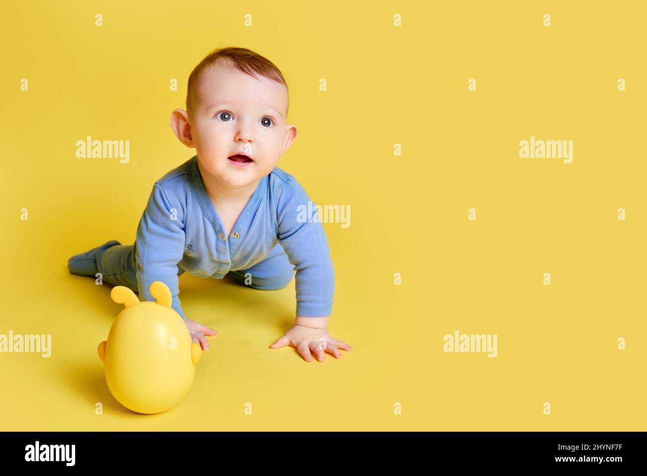 Curious toddler baby sits on studio yellow background. Funny child boy ...