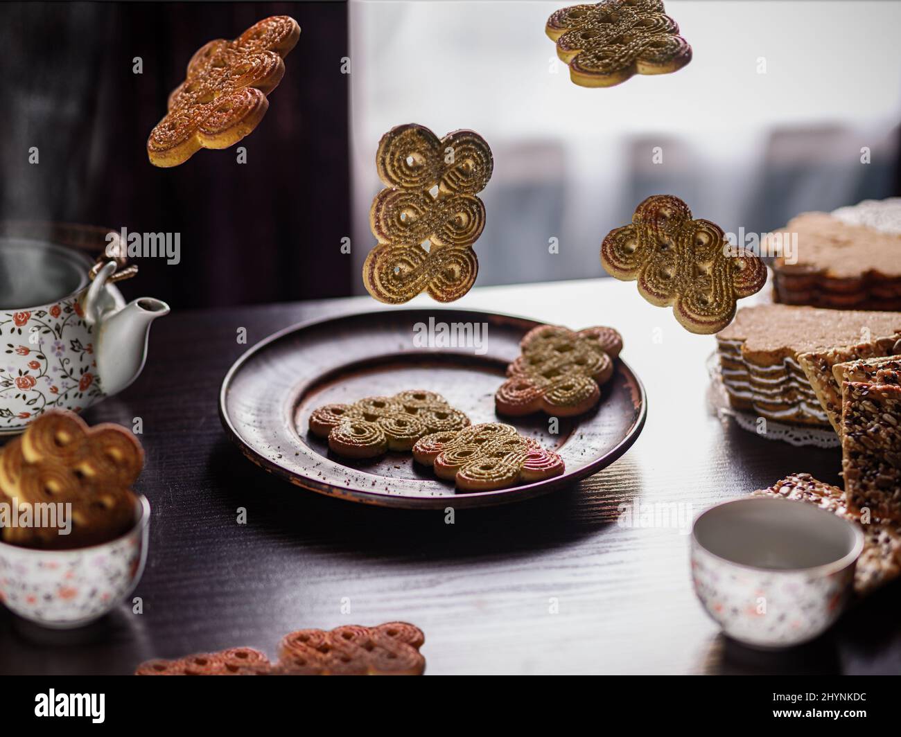 Group of flying sugar cookies and dishware on a brown table, isolated ...