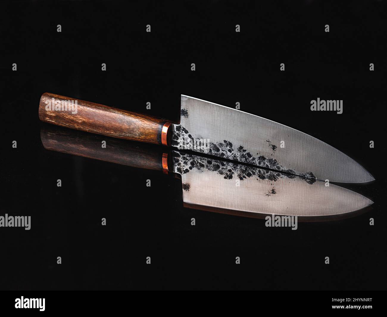 Sharp knife with a wooden handle and its reflection on a black surface ...