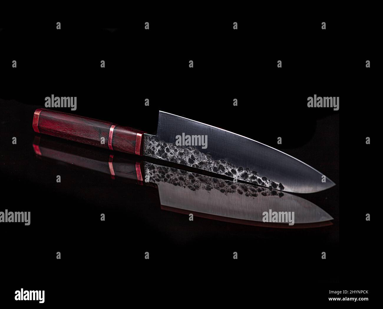 Sharp knife with a wooden handle and its reflection on a black surface ...