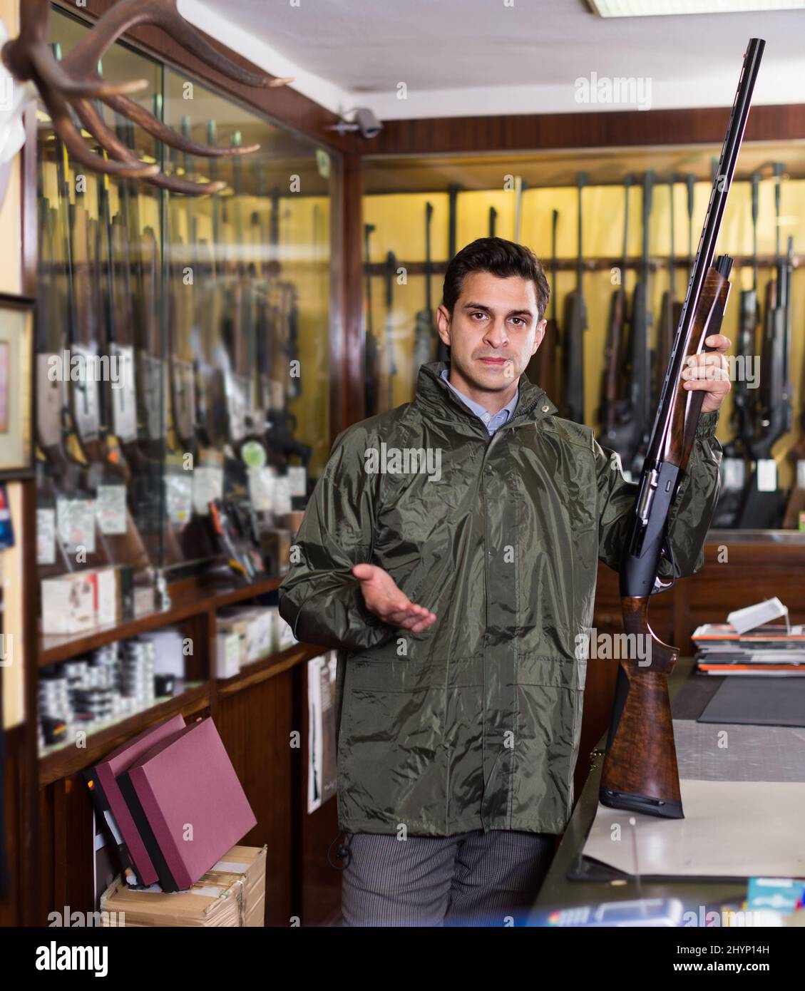 Modern male hunter choosing shotgun in store with hunt equipment Stock ...