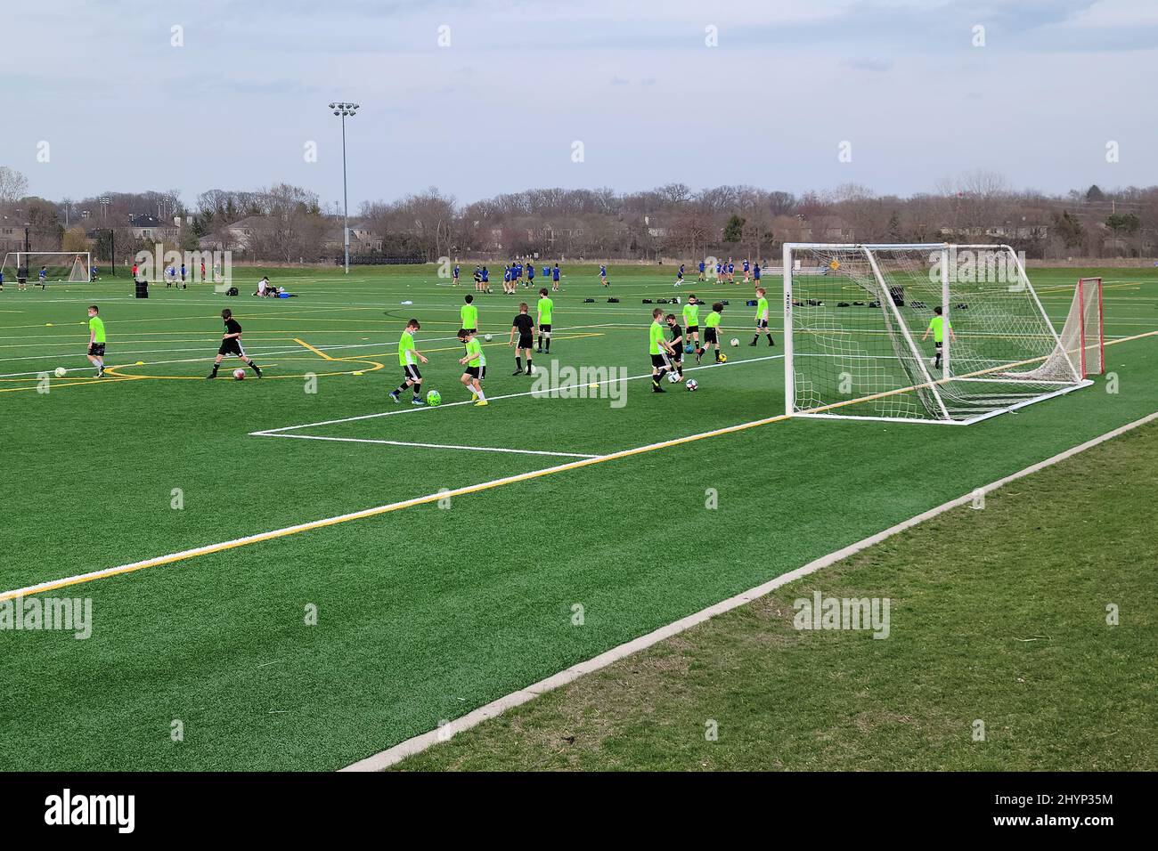 Boys practicing soccer on a multi-use ball field in early spring at a ...
