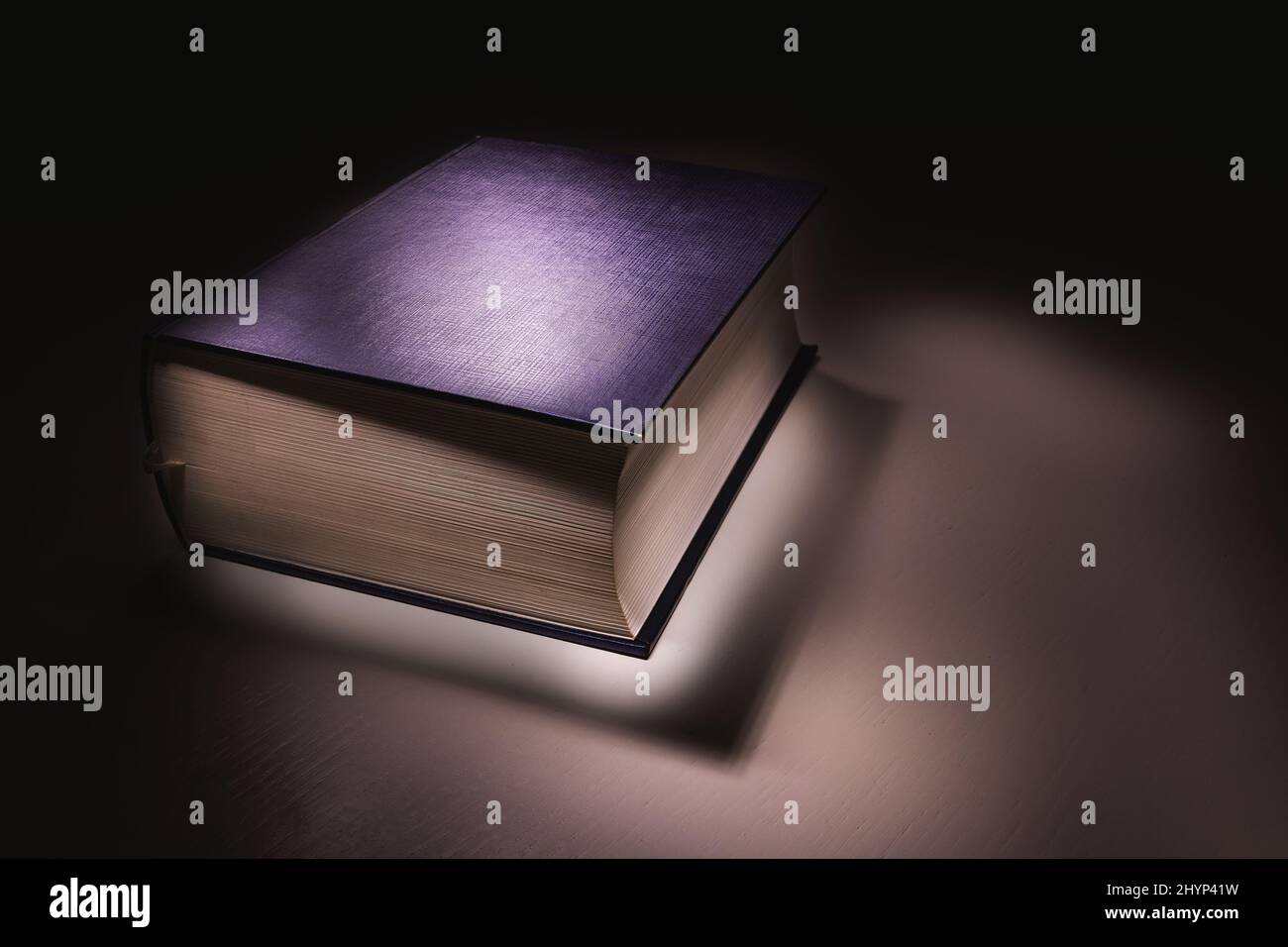 One big thick book on white table in the dark Stock Photo - Alamy