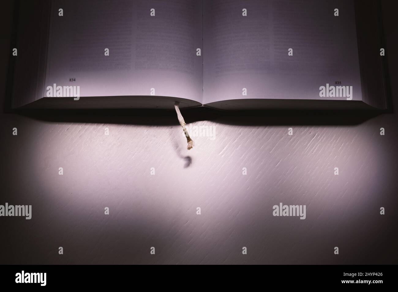 One open thick book on white table in the dark Stock Photo - Alamy