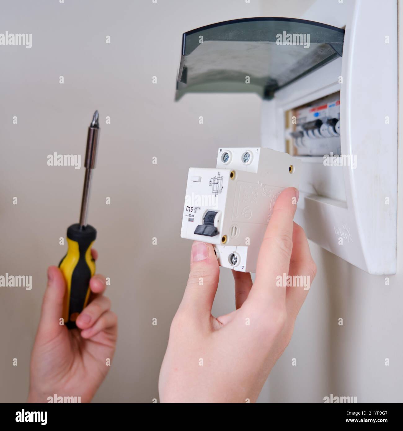 A woman changes an automatic fuse in a home electrical panel. Self ...