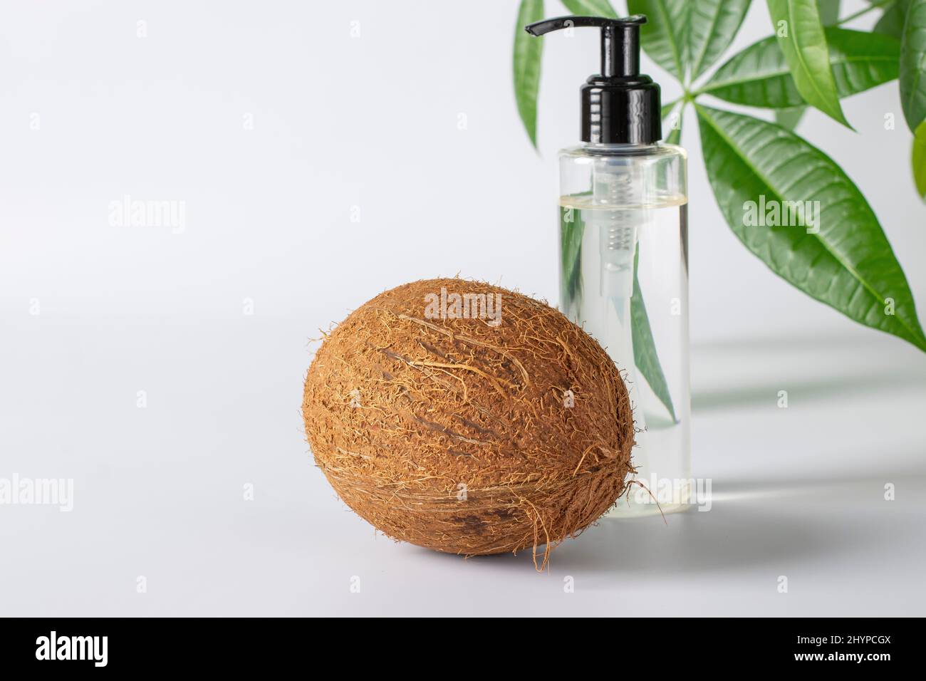Coconut oil in a transparent bottle and fresh coconut on a white ...