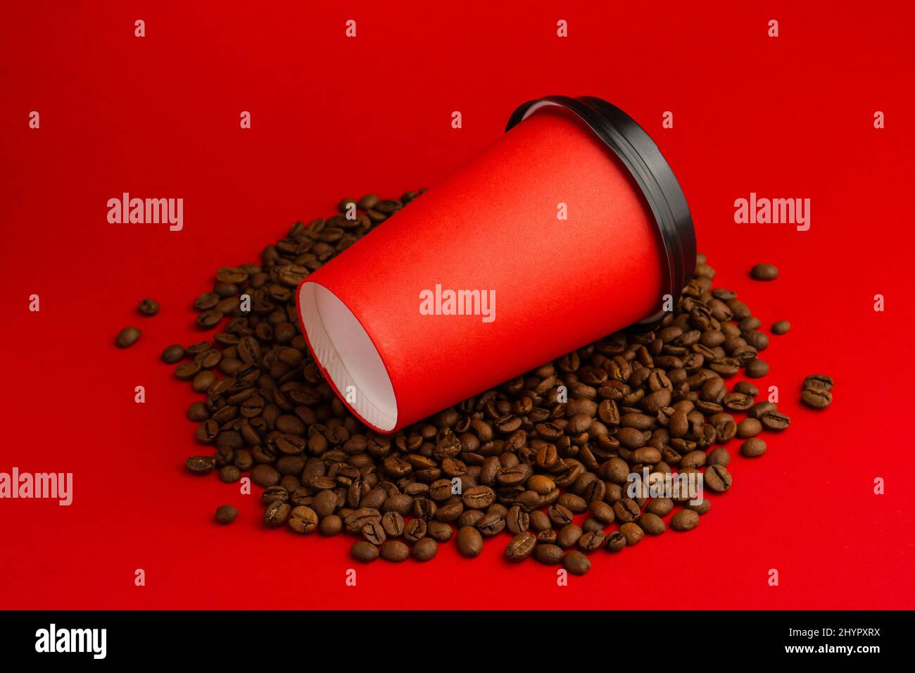 Takeaway red paper coffee cup with black cap lie on roasted beans at ...