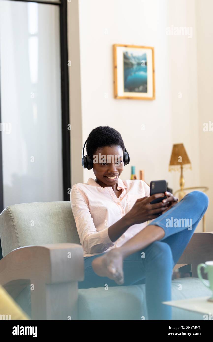 Happy african american woman using smartphone listening music through ...