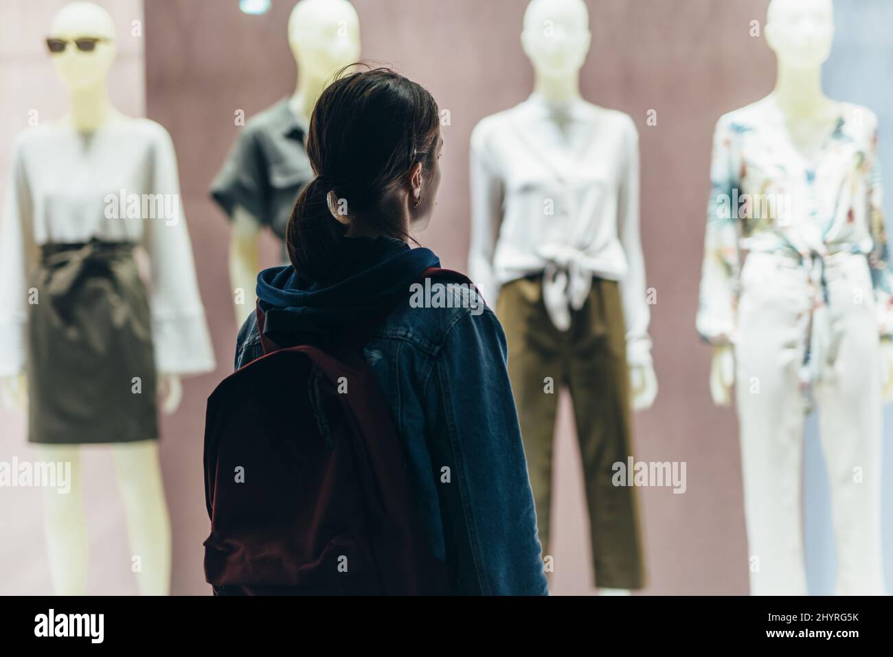 Young woman looks at women's clothes in the window Stock Photo - Alamy