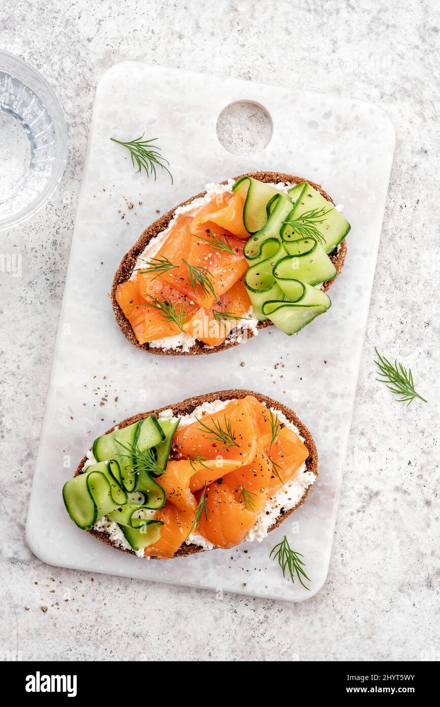 Rye bread open sandwiches with salted salmon and cucumber on a white ...