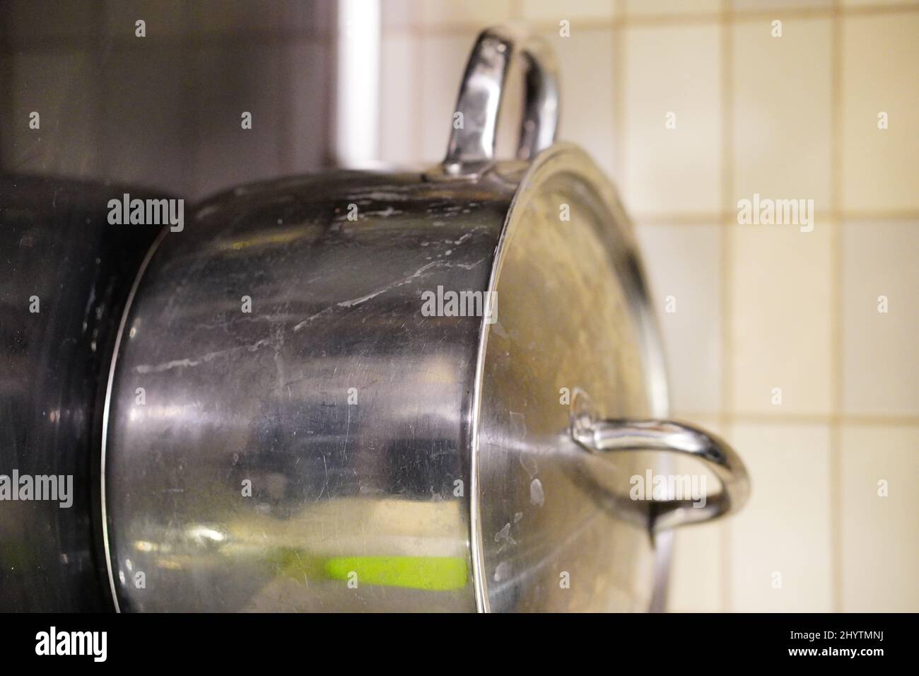 Vertical closeup shot of a metal pot with a cover on an induction hob ...