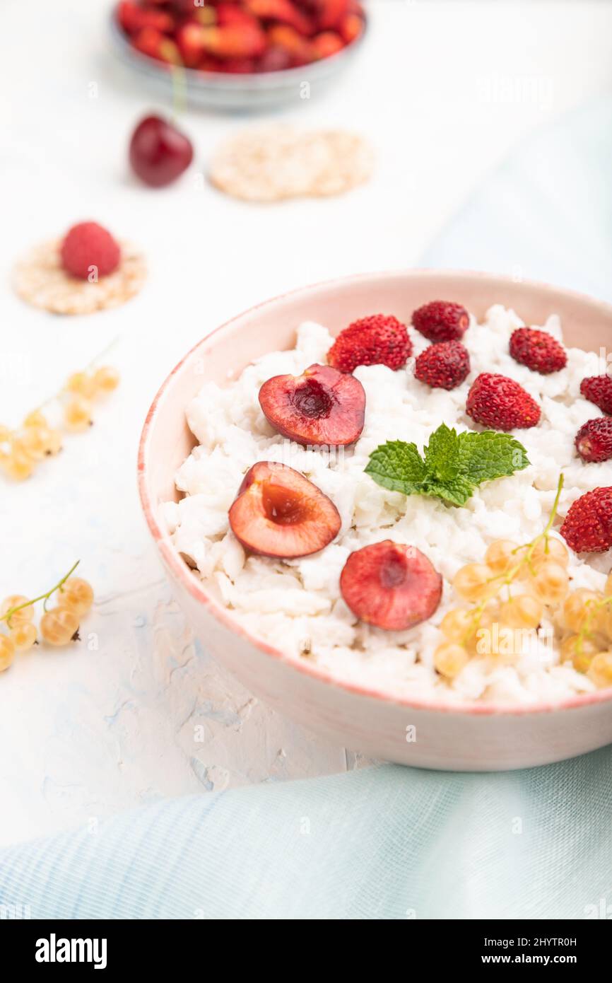 Rice flakes porridge with milk and strawberry in ceramic bowl on white ...