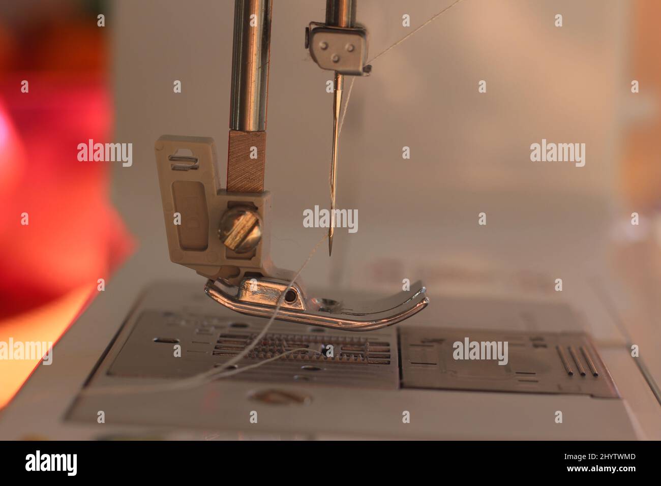 Closeup shot of a sewing machine needle with its foot seen in profile ...