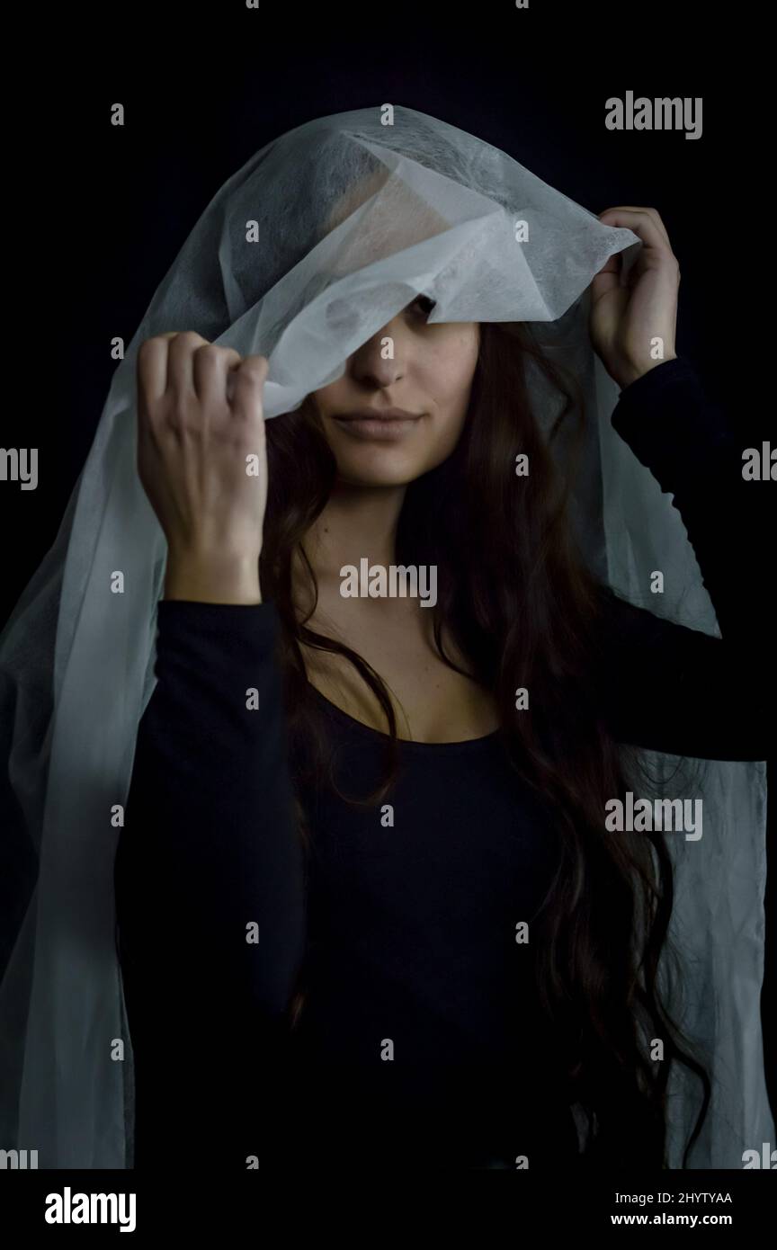 Portrait of a beautiful young woman with a transparent white fabric ...