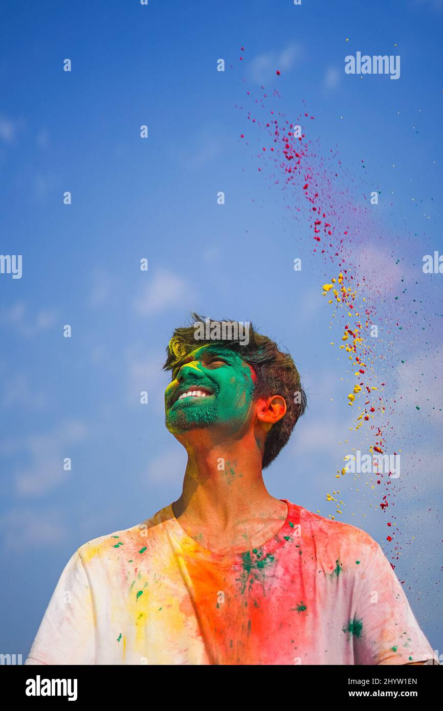 Vertical closeup of the young man covered in bright colors. Holi ...