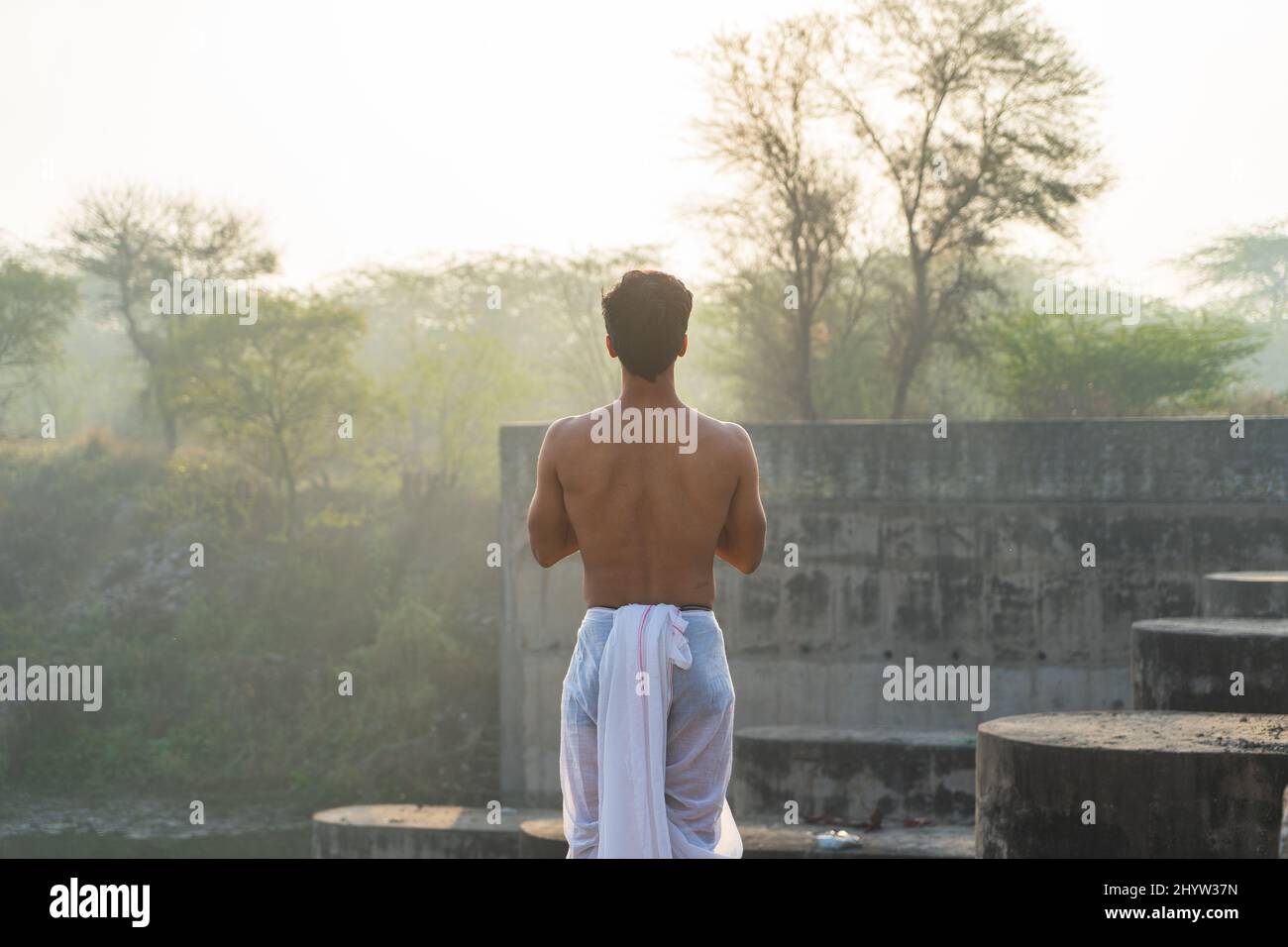 Young Indian priest praying to the sun early in the morning while ...