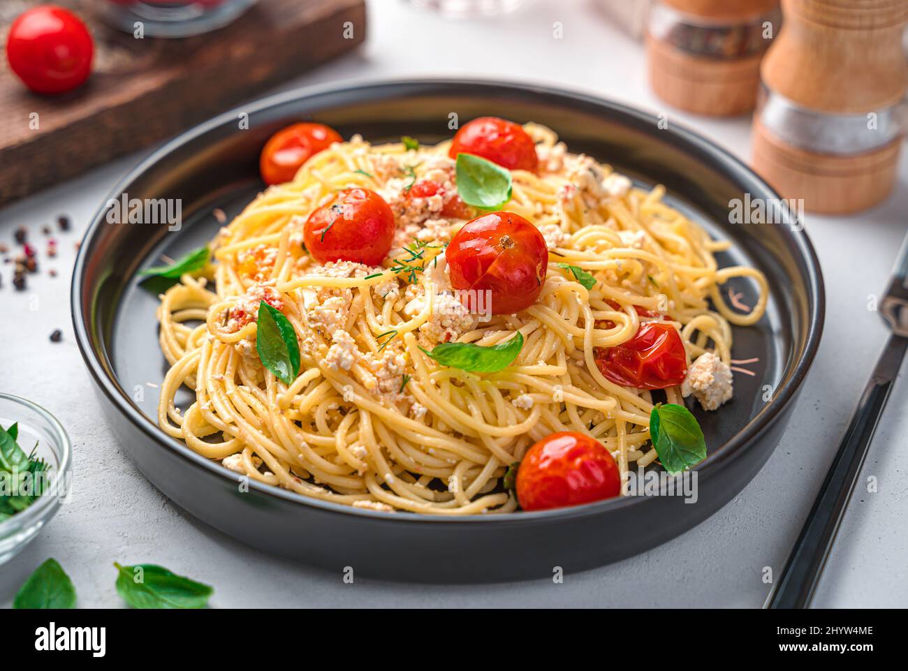 Spaghetti with baked feta and cherry tomatoes on a gray background ...