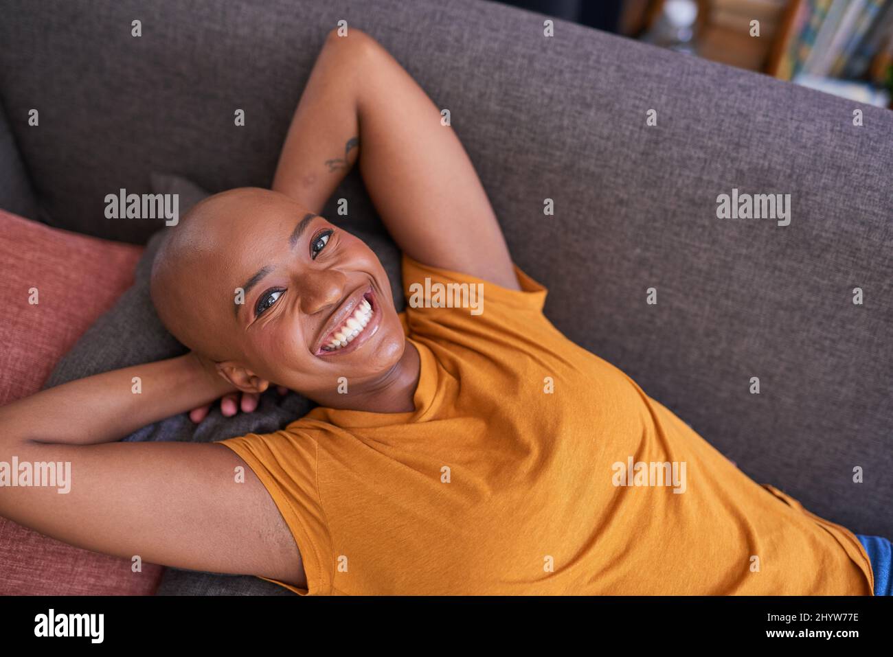 A young woman relaxes on the sofa with her arms behind her head Stock ...