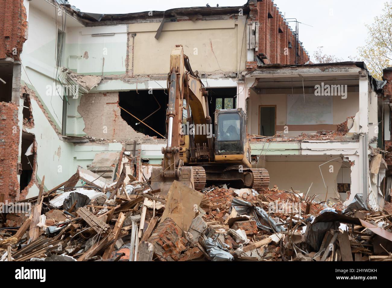 Excavator on pile debris in front of a ruined old house Stock Photo - Alamy