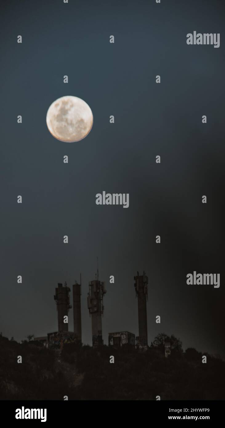 Shot of an industrial area over high land with full moon in the sky ...