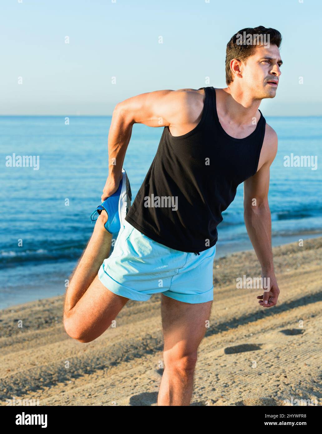 Physically fit man doing stretching exercises on morning beach Stock ...