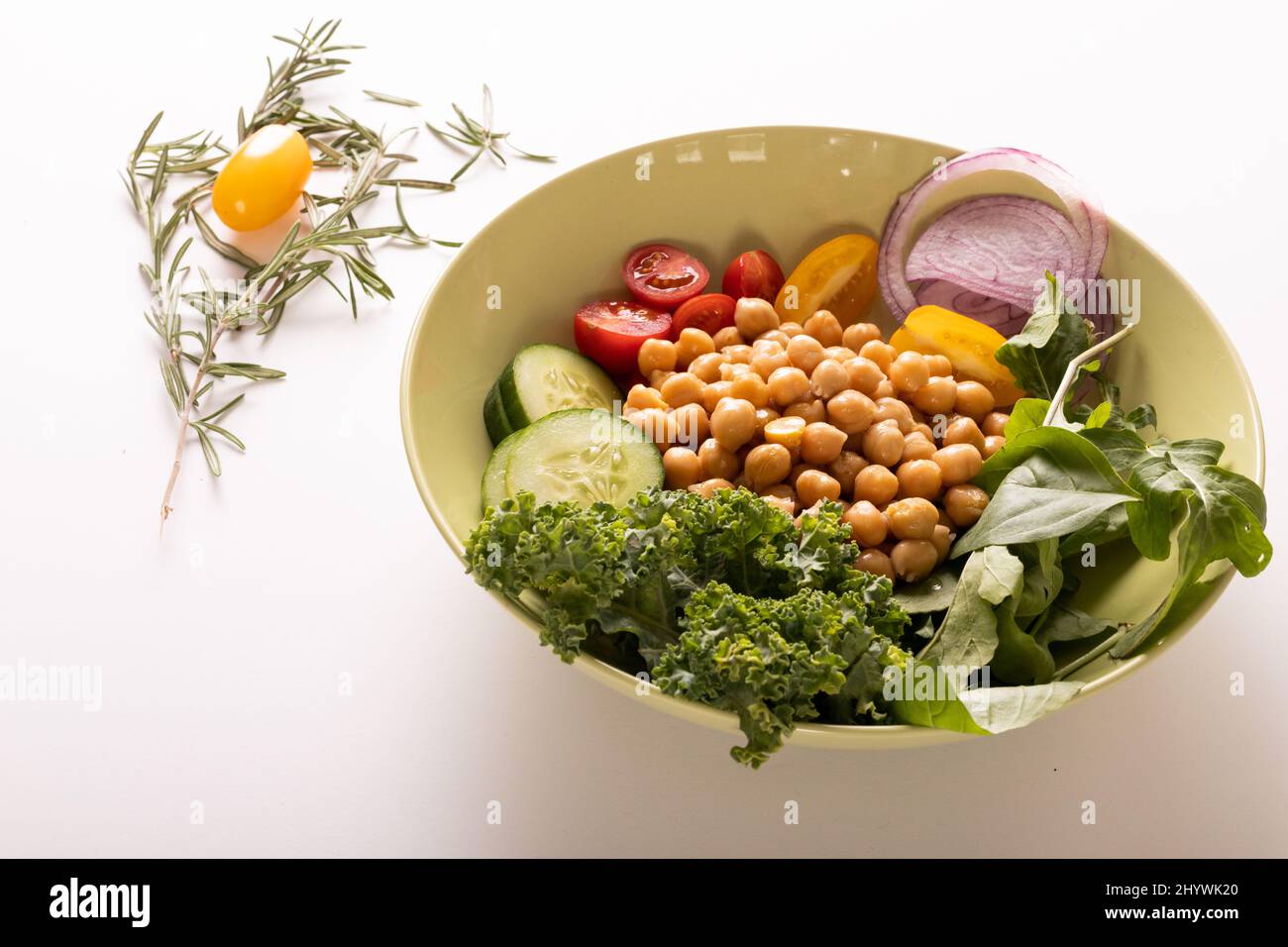 Close-up of fresh healthy food in bowl by herb on white background ...