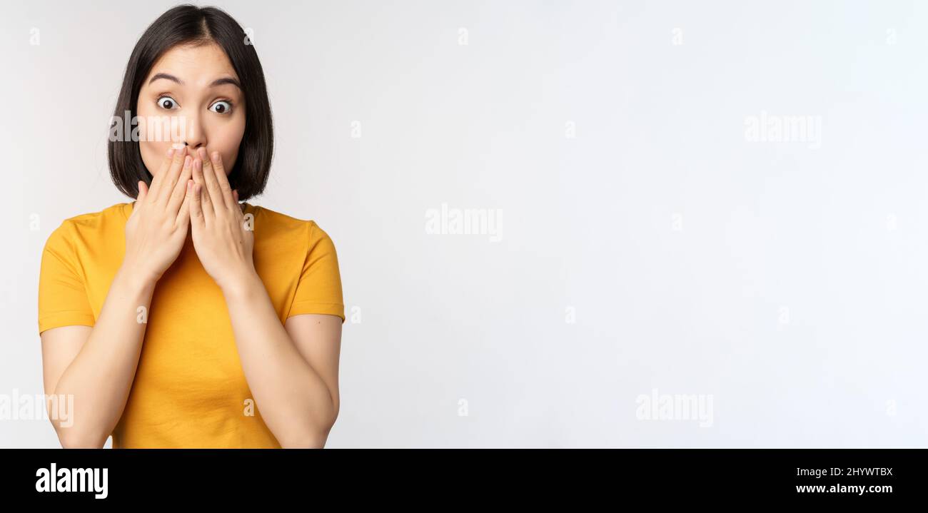 Surprised asian woman gasping, cover mouth with hands and looking ...