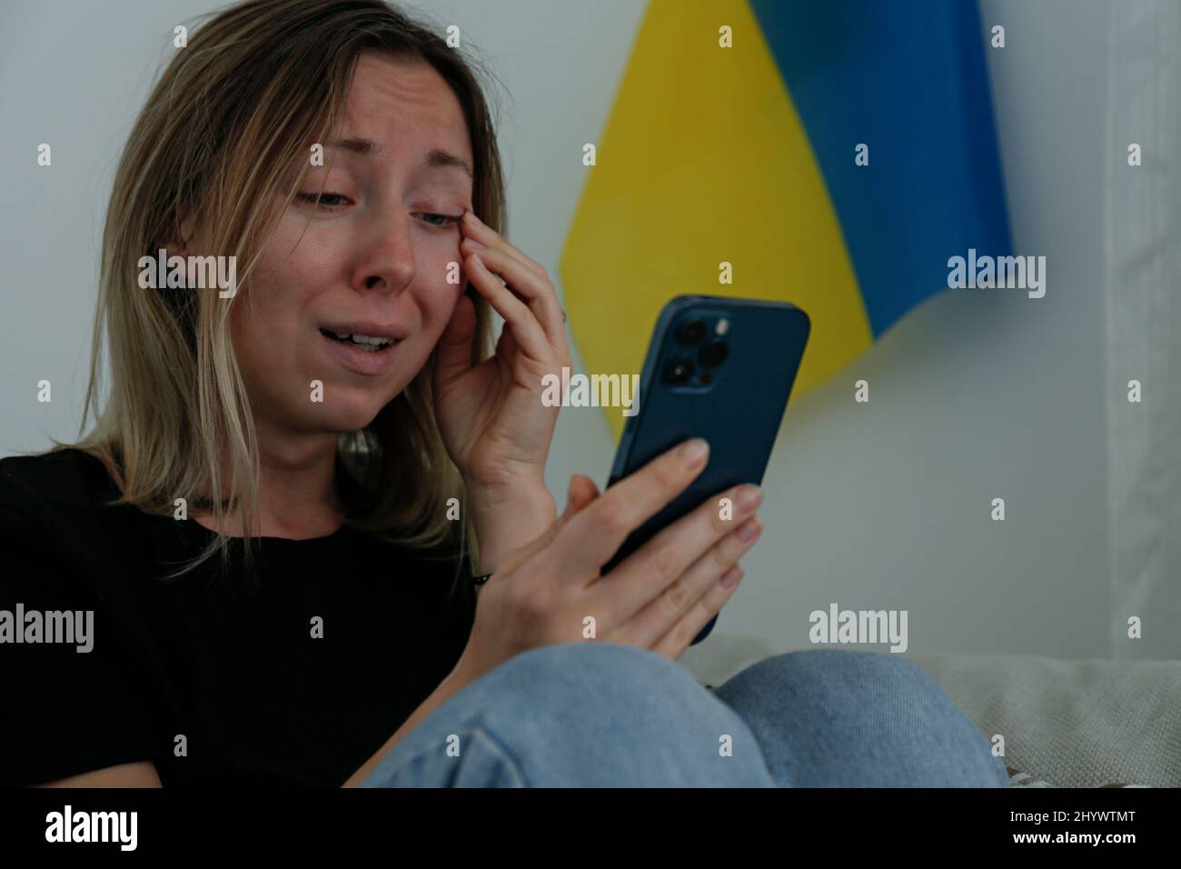 Young anxious woman with cried out eyes reading the news about Ukraine ...